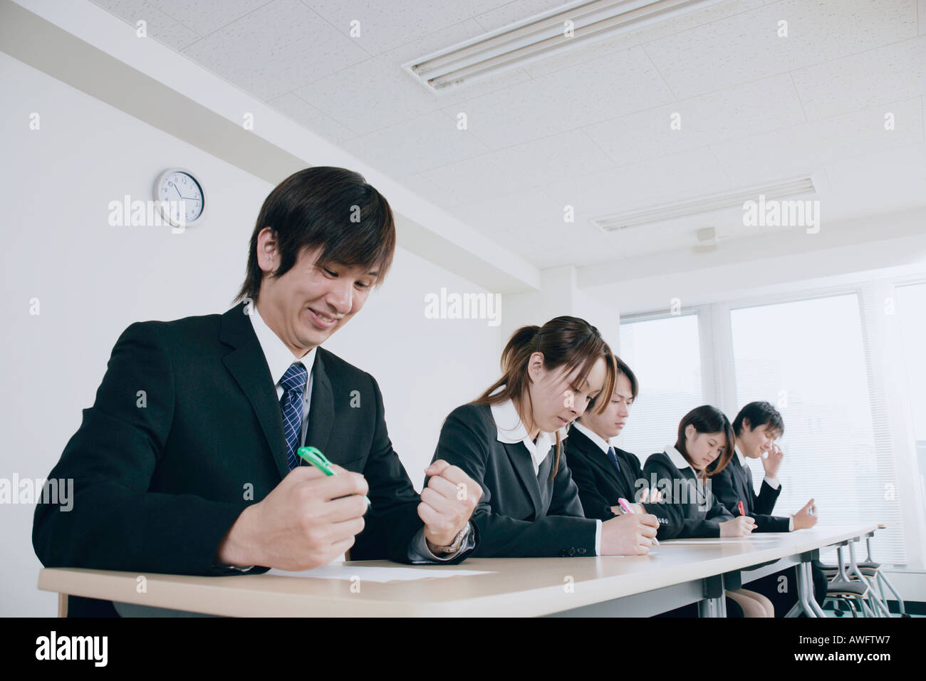 Five young people writing on exam paper Stock Photo - Alamy