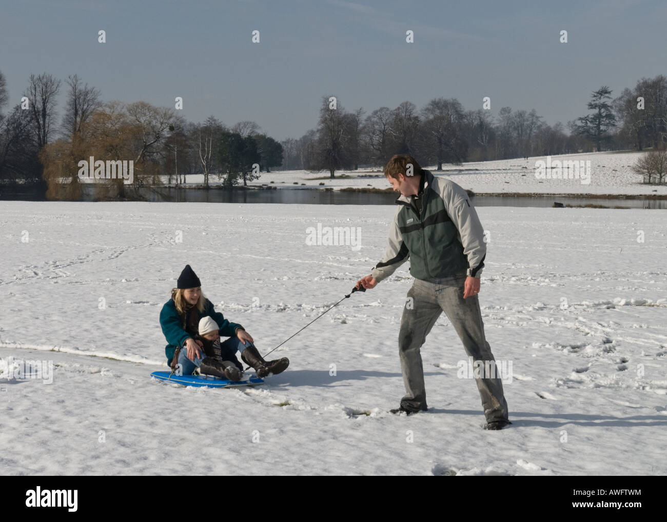 father pulling wife and one year old baby on sledge over snow Stock ...