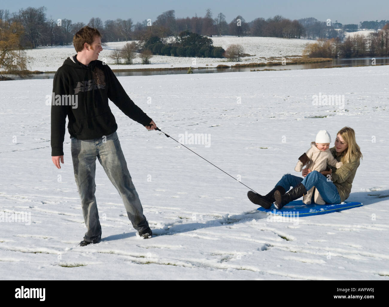 father pulling wife and one year old baby on sledge over snow Stock ...