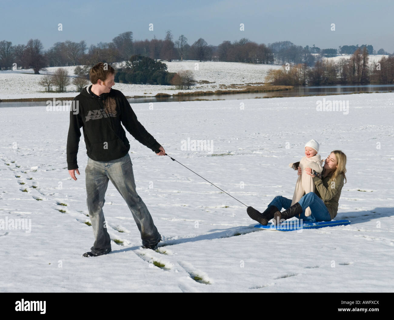 father pulling wife and one year old baby on sledge over snow Stock ...
