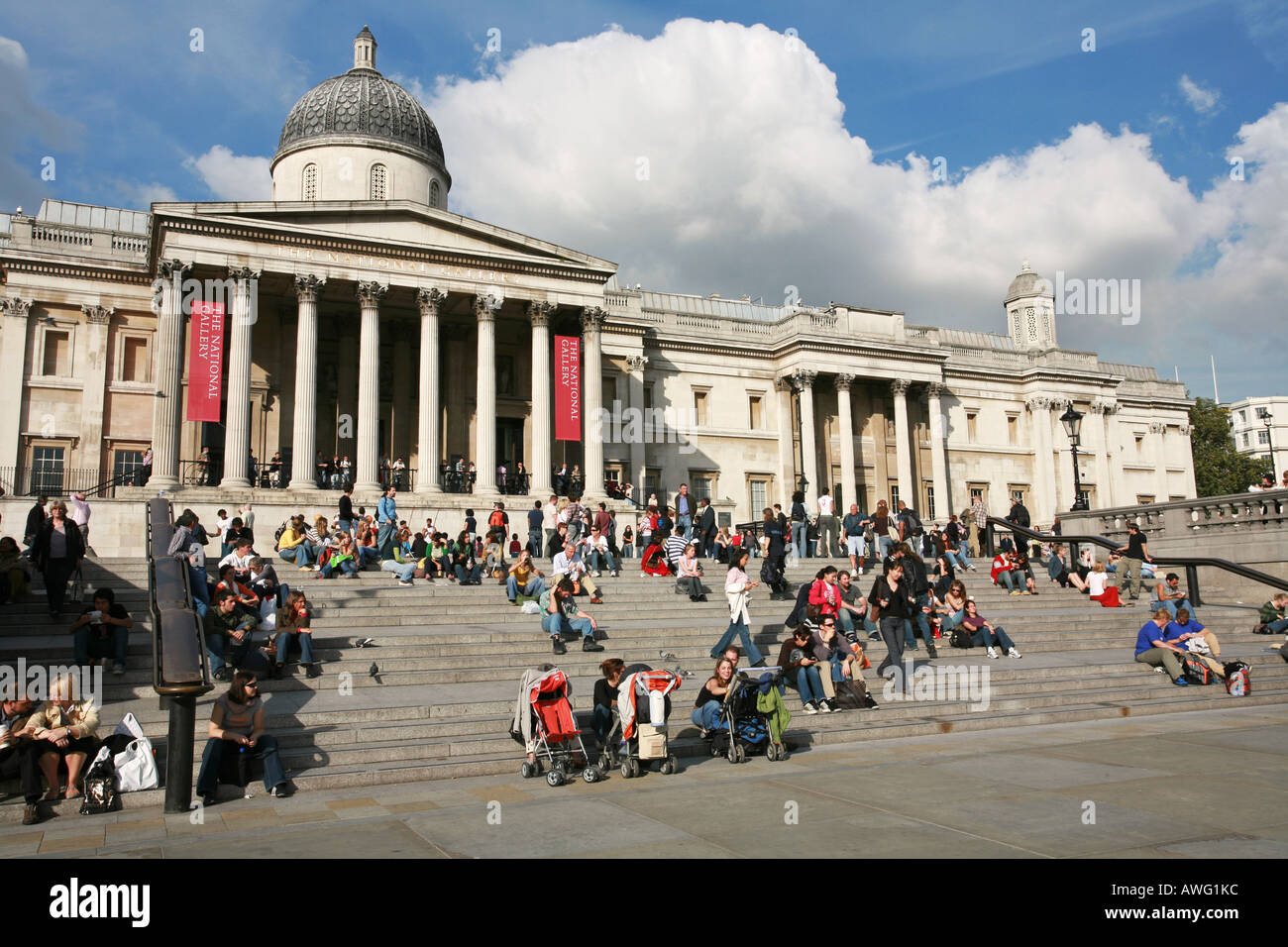 Tourists sightseeing in Trafalgar Square sit on steps outside the ...