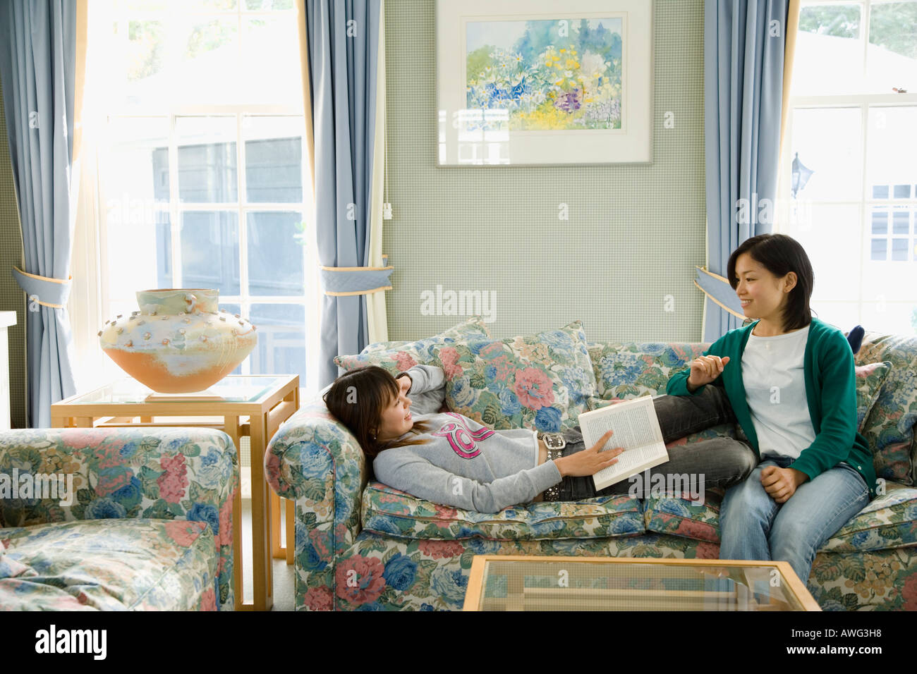 Two young women talking on sofa Stock Photo - Alamy