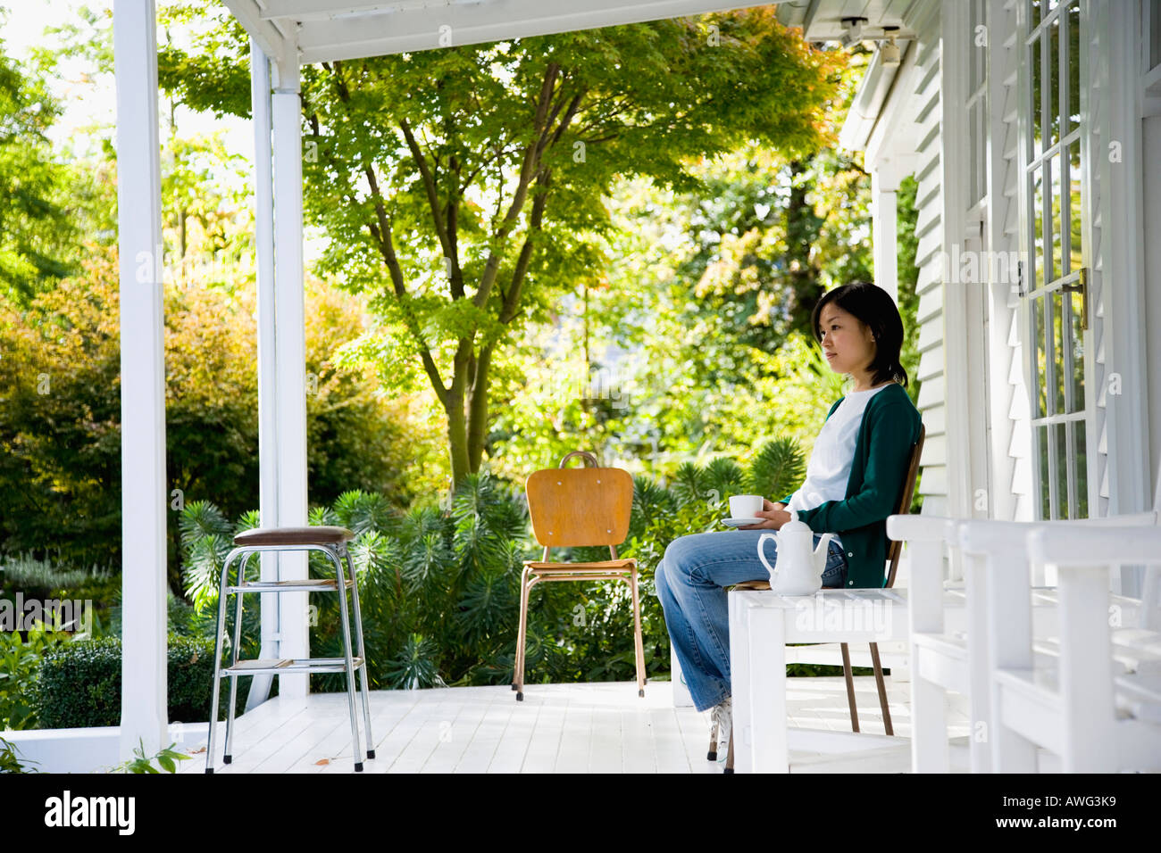 Young woman sitting on porch Stock Photo - Alamy