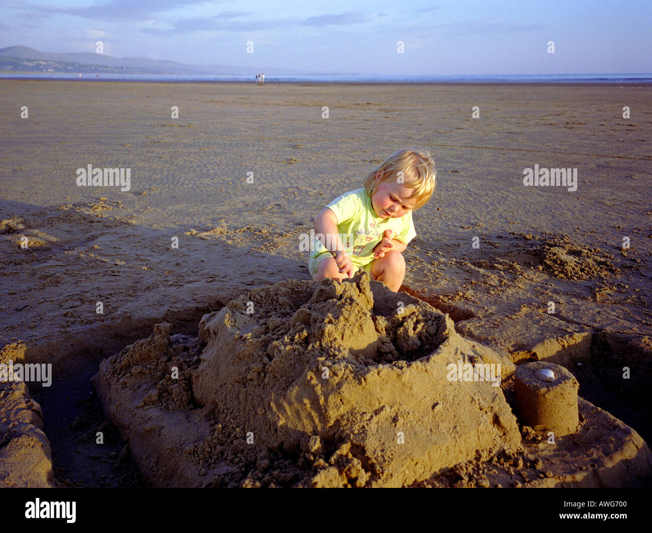Young girl building a sand castle on a beach in summer Stock Photo - Alamy