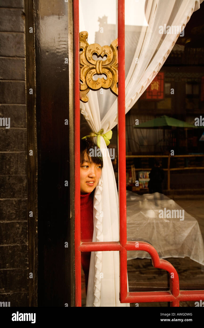 A waitress looks out of the window of a restaurant in Pingyao, People's ...