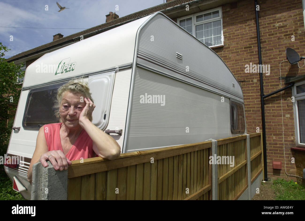 Old woman stands by a caravan at her home as a bird flys by UK Stock ...