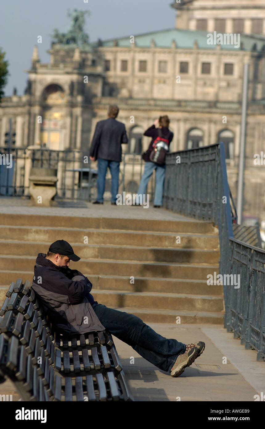 Man snoozing at the bench with tourists making pictures behind Stock ...