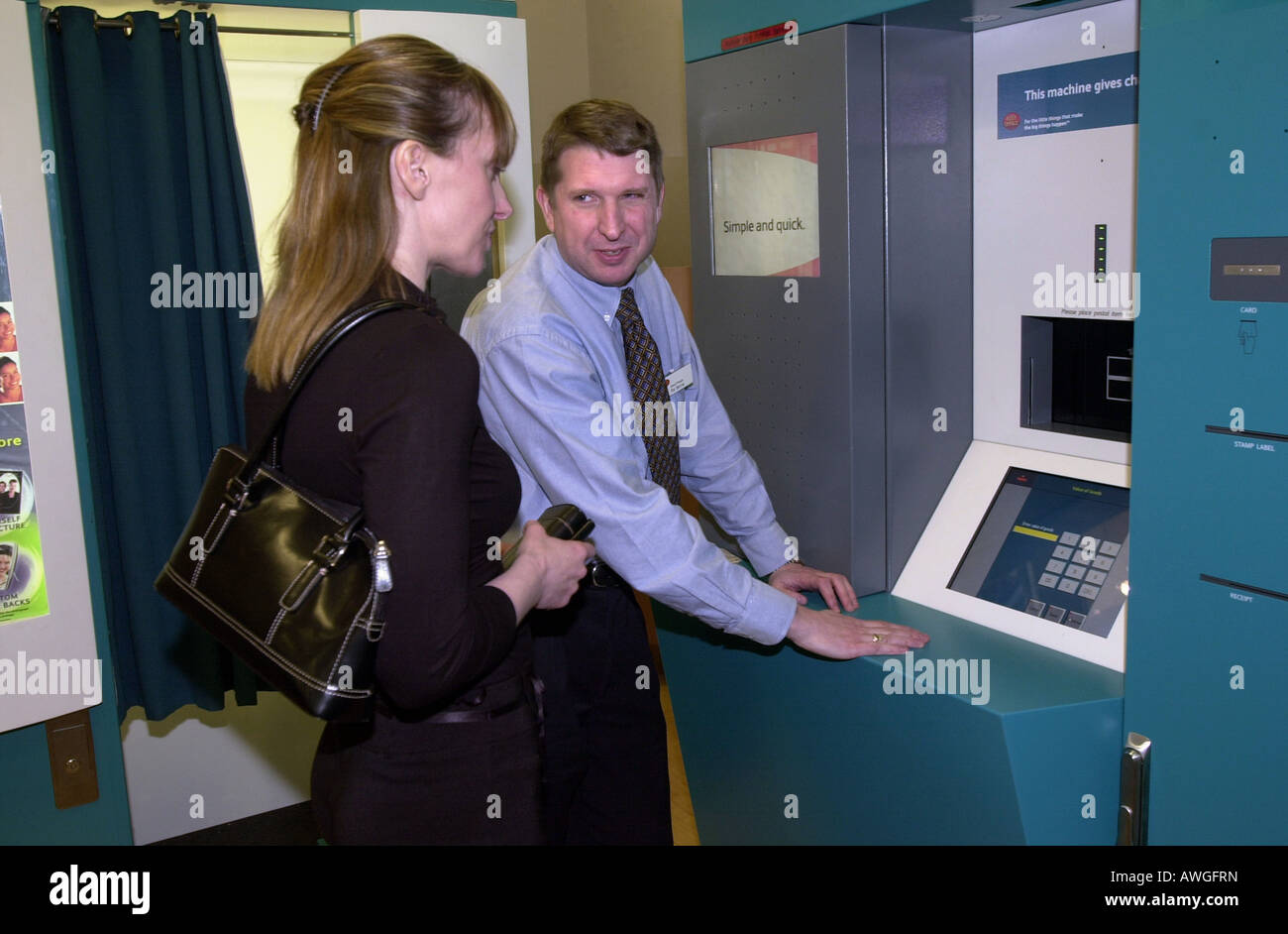 A postal officer shows a member of the public how use an automatic ...