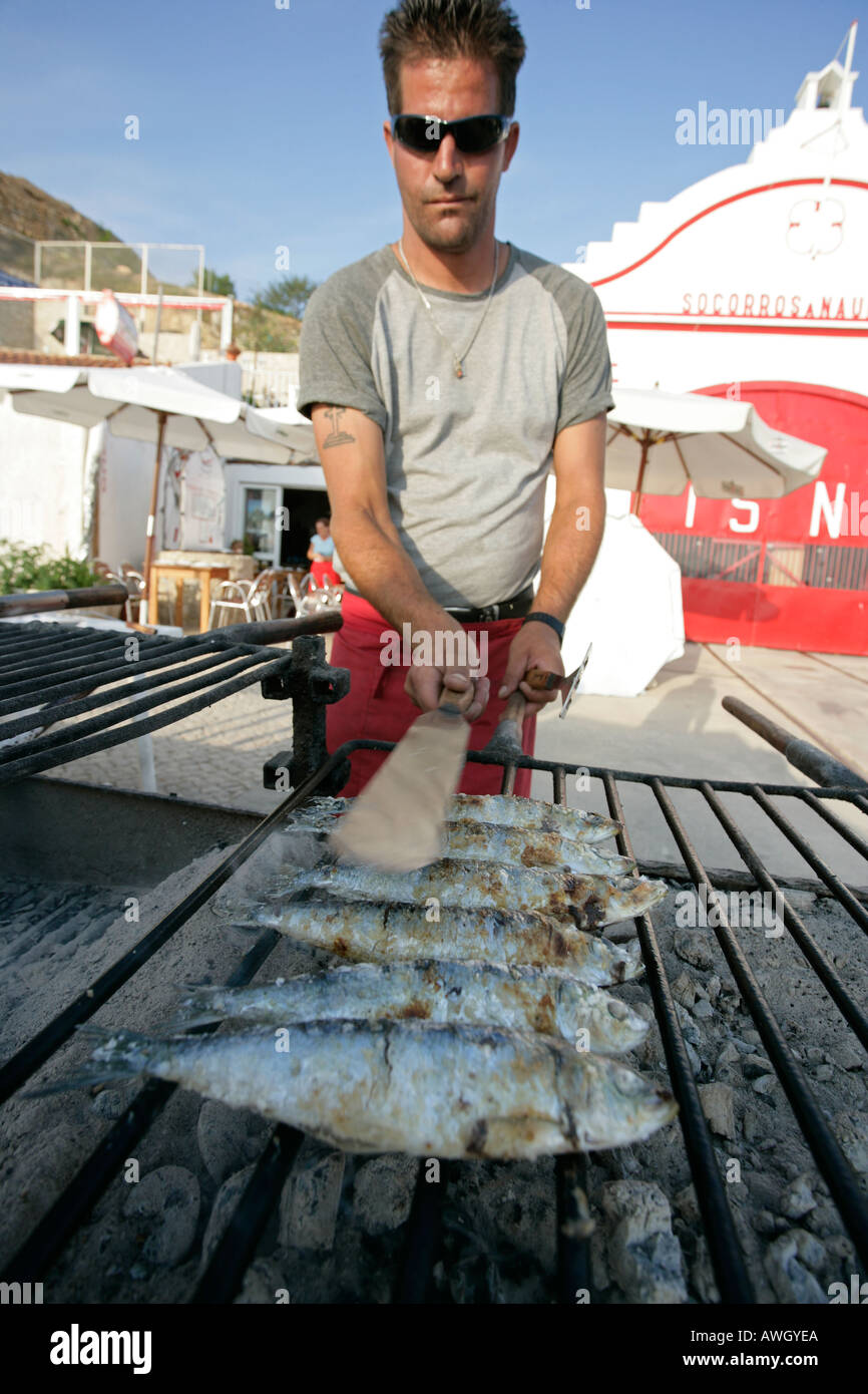 A Portuguese man grills sardines over a charcoal fire outside a ...