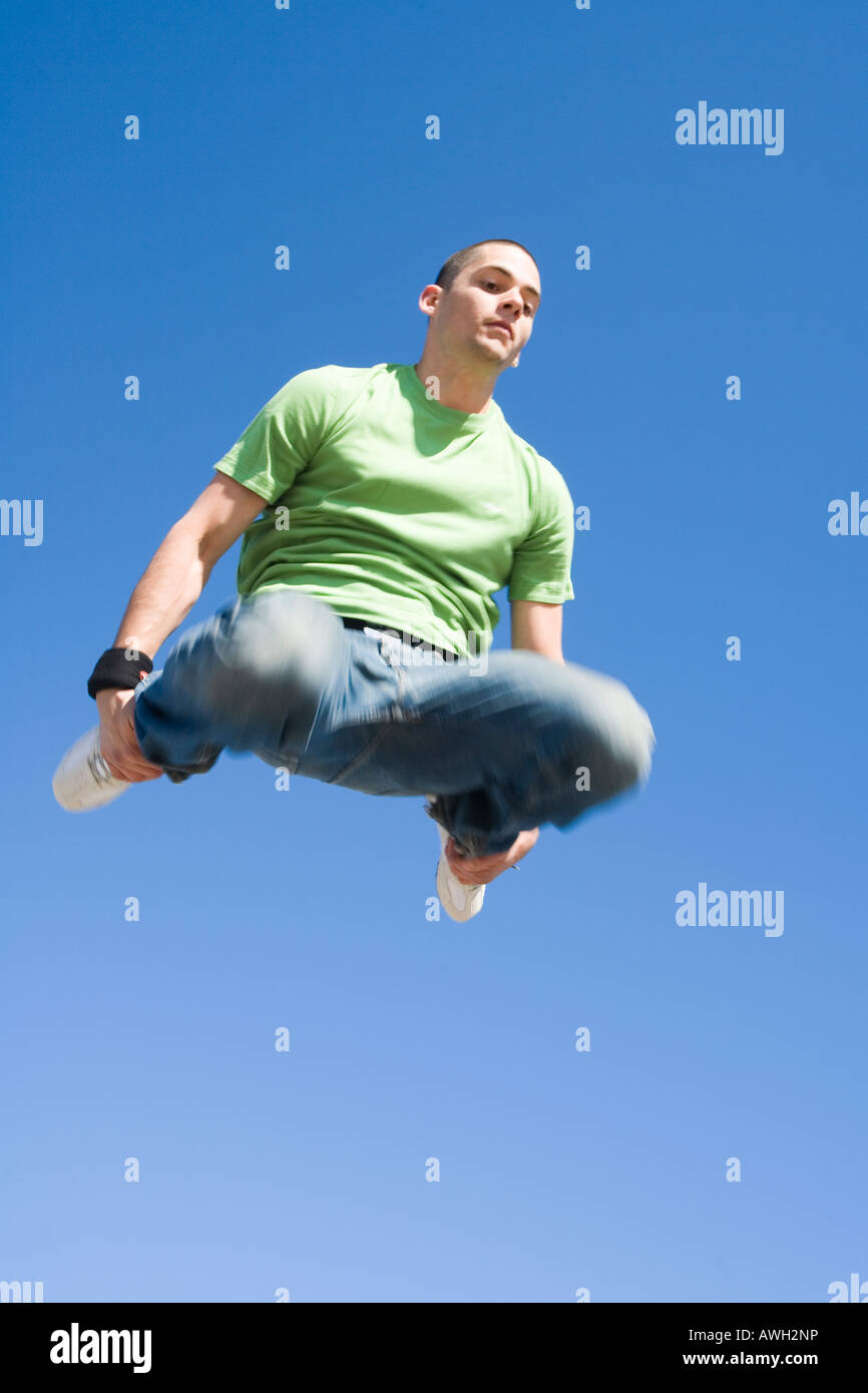 Young man jumping trough the sky holding his feet Stock Photo - Alamy