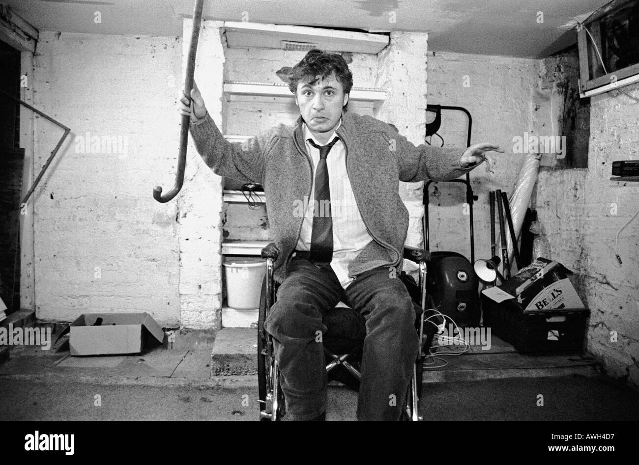 A discontented man in a wheelchair waving a walking stick angrily Stock ...