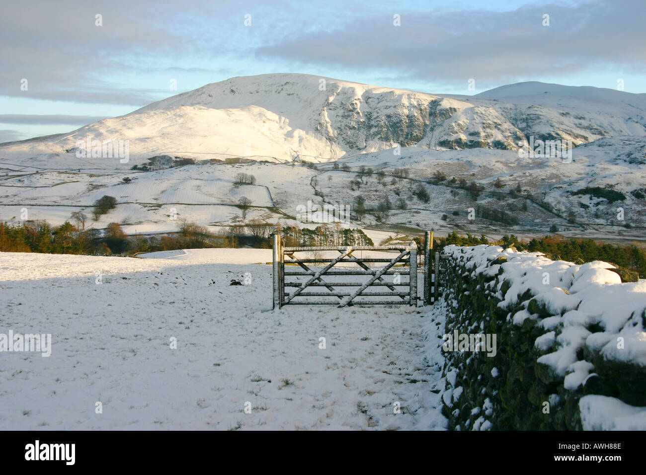 snow covered dry stone wall at Castlerigg stone circle and mountains ...