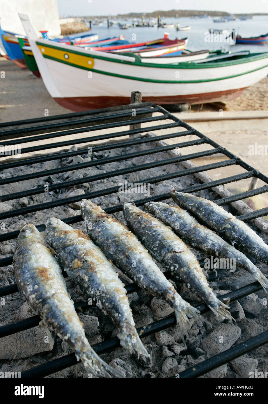 sardines cook over a charcoal fire outside a restaurant on the beach at ...