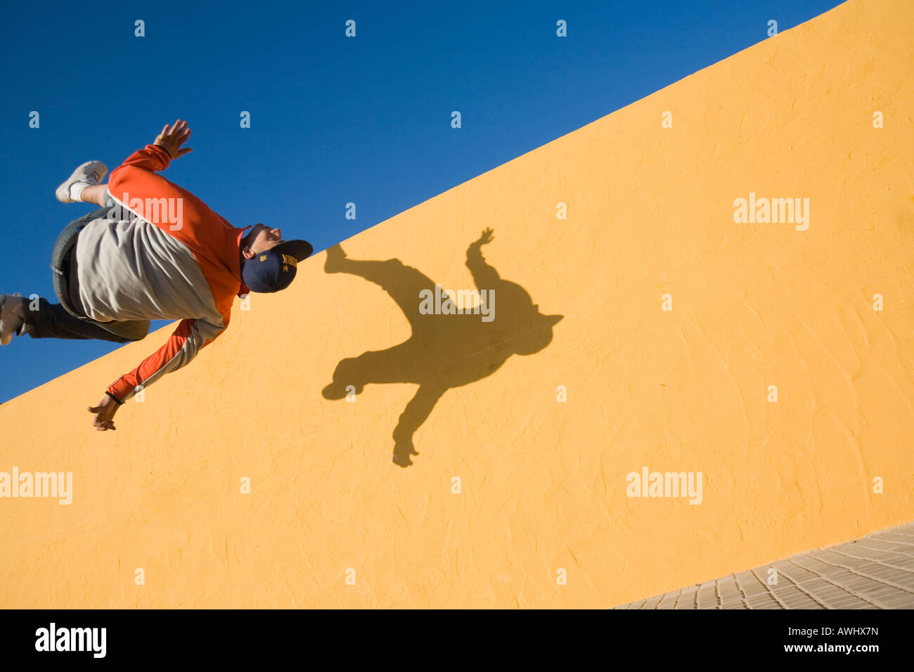 Young man somersaulting with yellow wall in background Stock Photo - Alamy