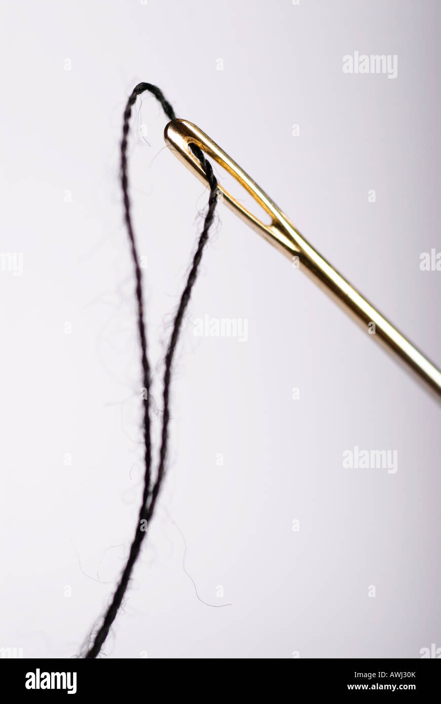 Stock photo of a black piece of thread threaded through the eye of a ...