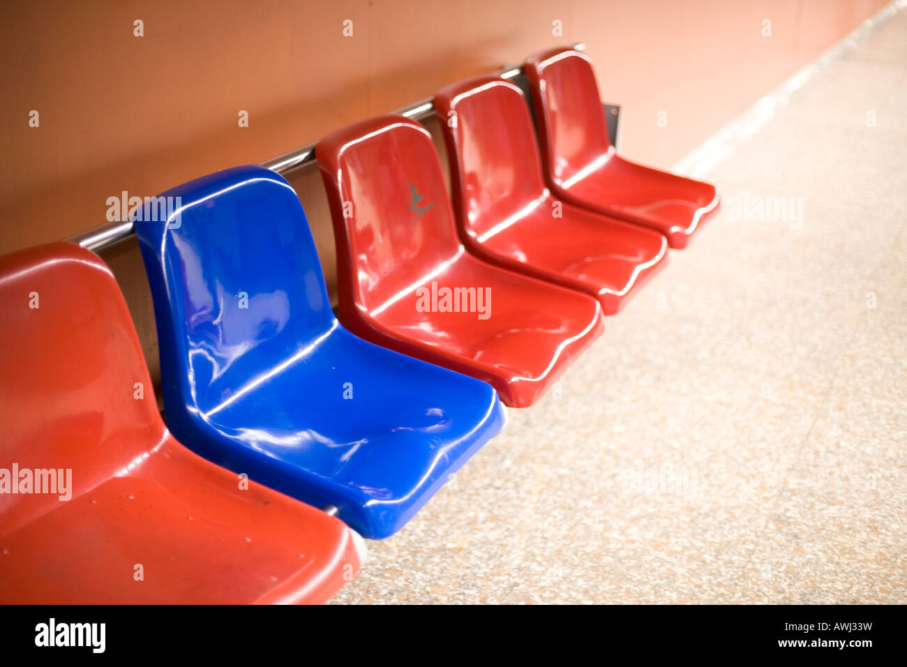 blue plastic seat between four red plastic seats Stock Photo - Alamy