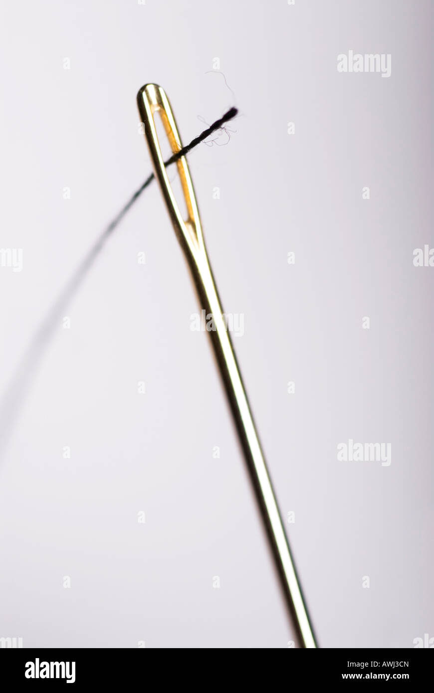 Stock photo of a black piece of thread threaded through the eye of a ...