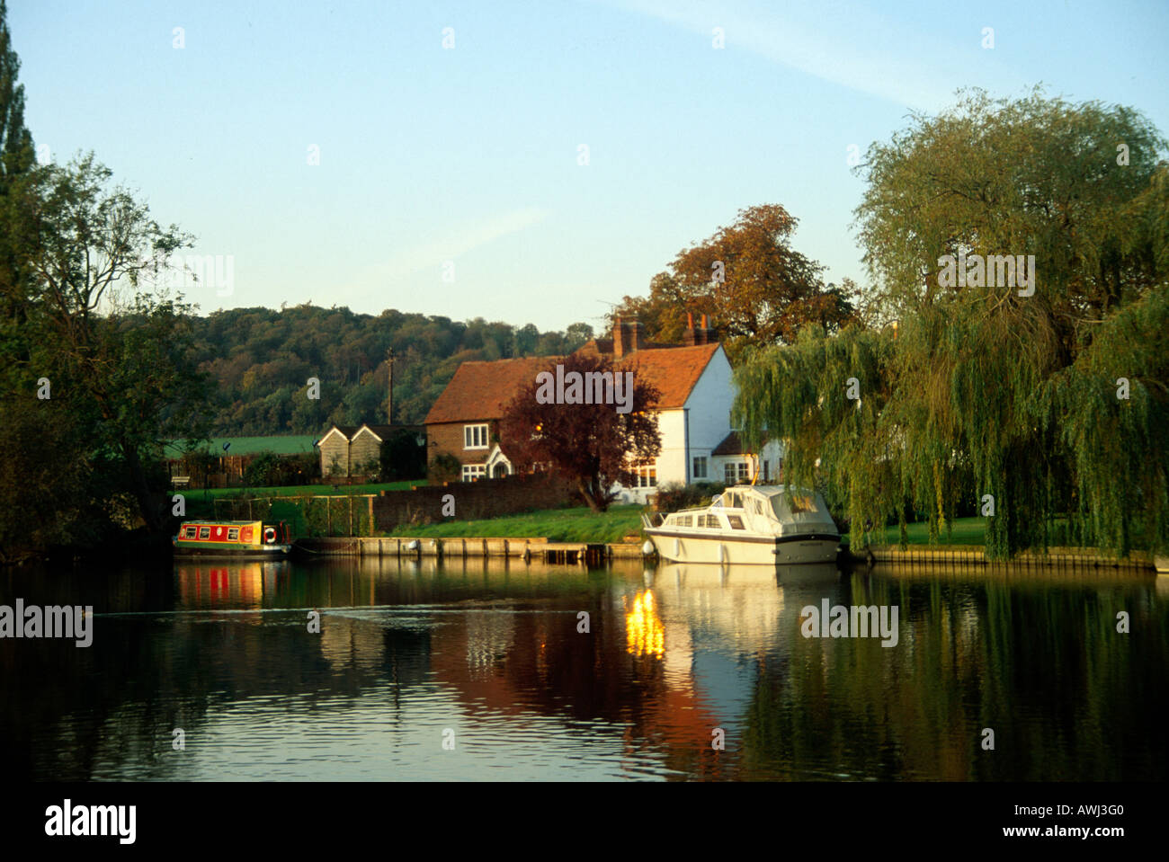 Mill End House by the River Thames in evening sunlight with moored ...