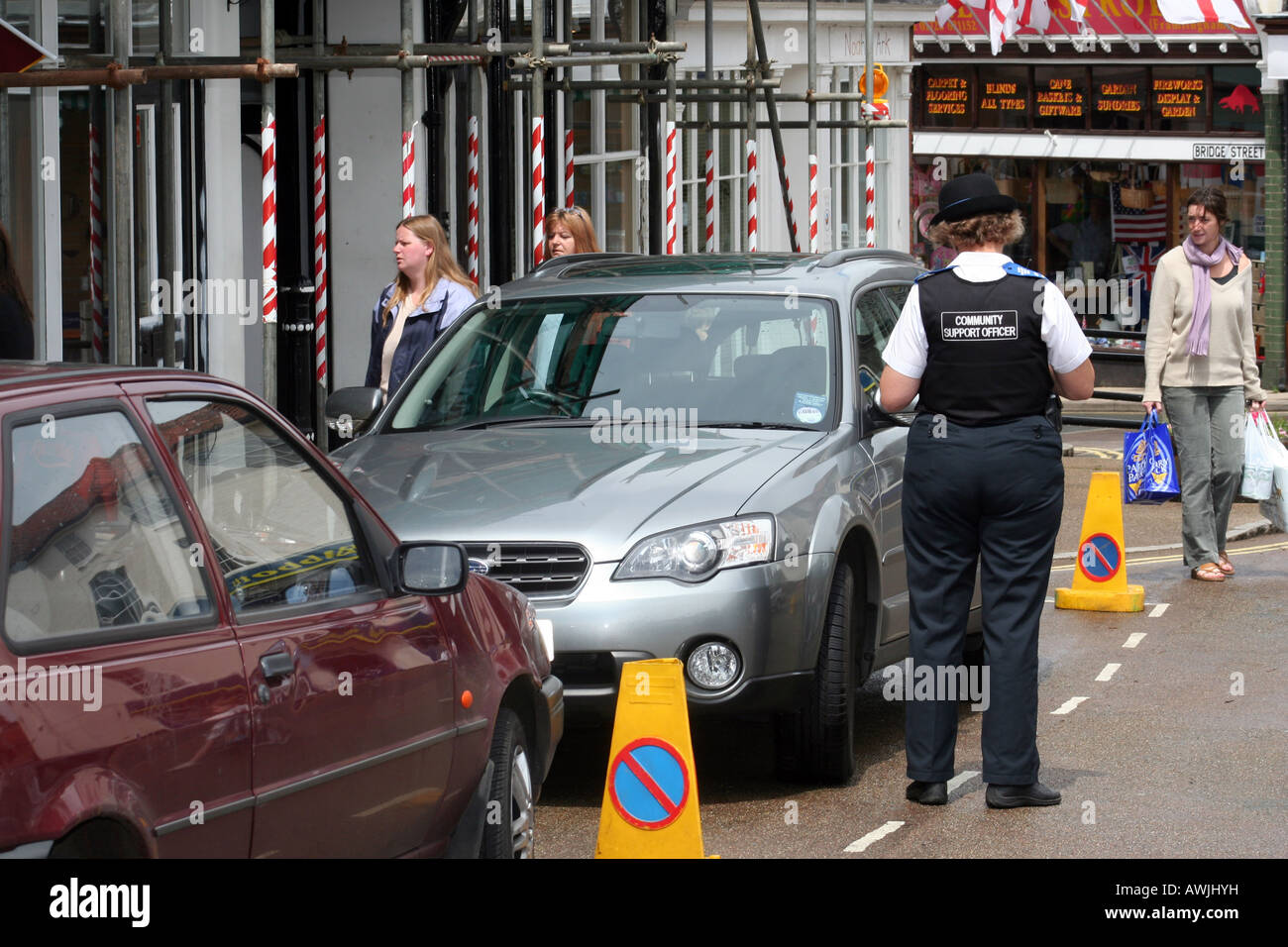 A female police community support officer takes notes about cars parked ...