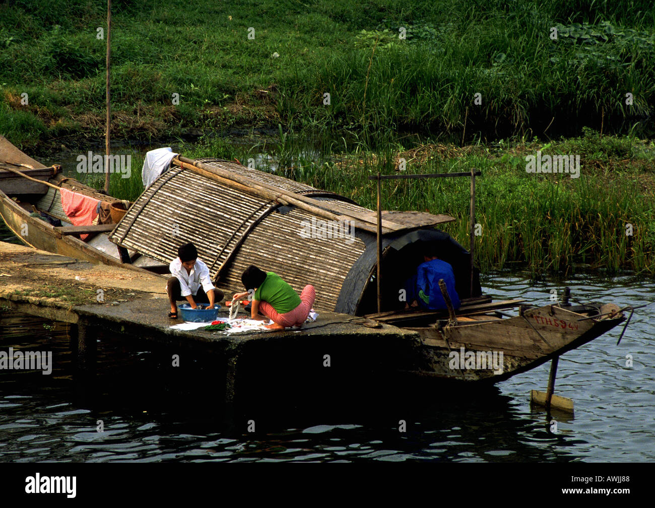 Vietnam, people doing laundry on dock next to houseboat Stock Photo - Alamy