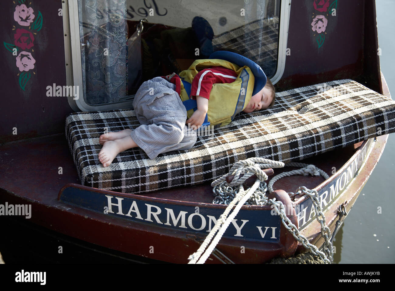 boy child sleeping on front of longboat near Goring on River Thames ...