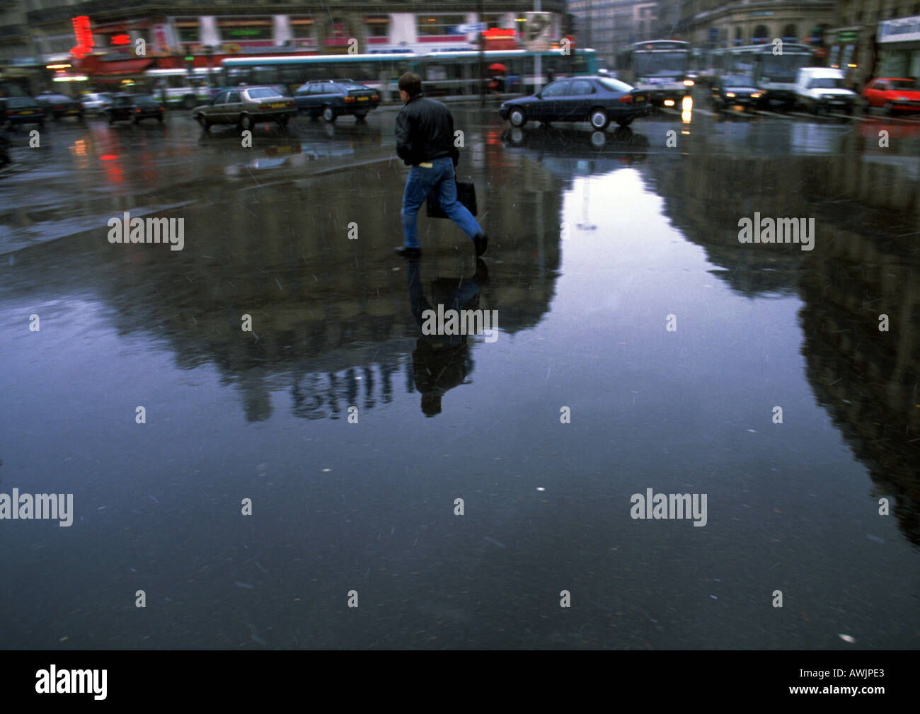 Person walking through square on wet ground with reflection Stock Photo ...