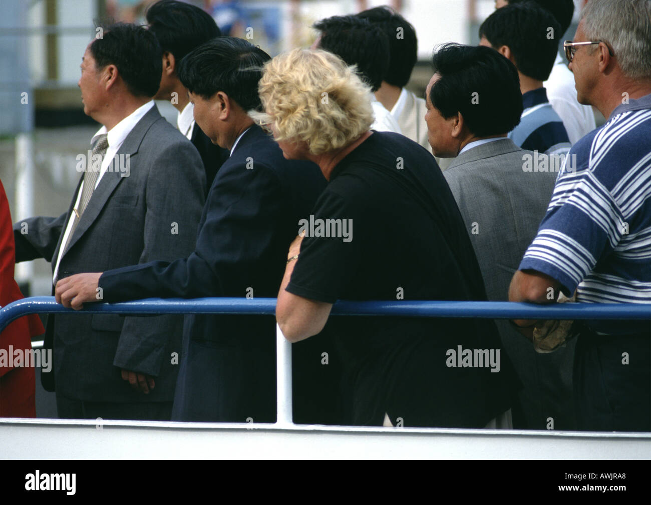 Crowd waiting by railing Stock Photo - Alamy