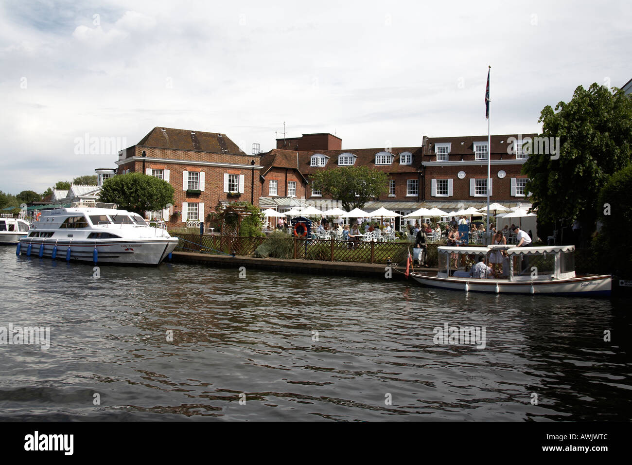 The Compleat Angler hotel garden with people dining and moored cabin ...