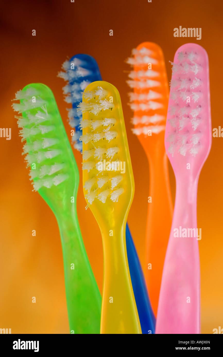 Five colorful toothbrushes against an orange background Stock Photo - Alamy