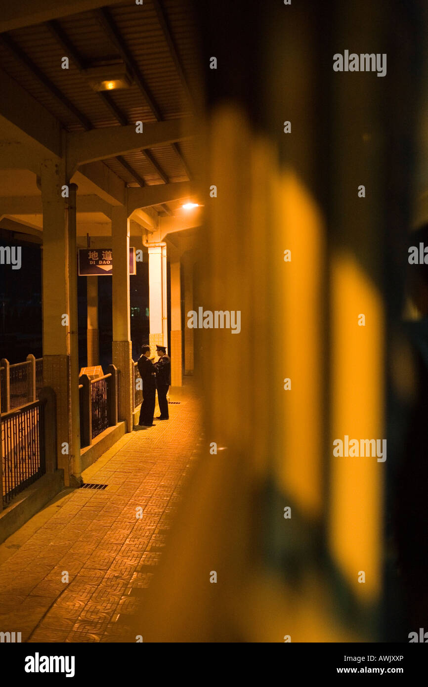 Two guards talking together on the train station platform at night ...