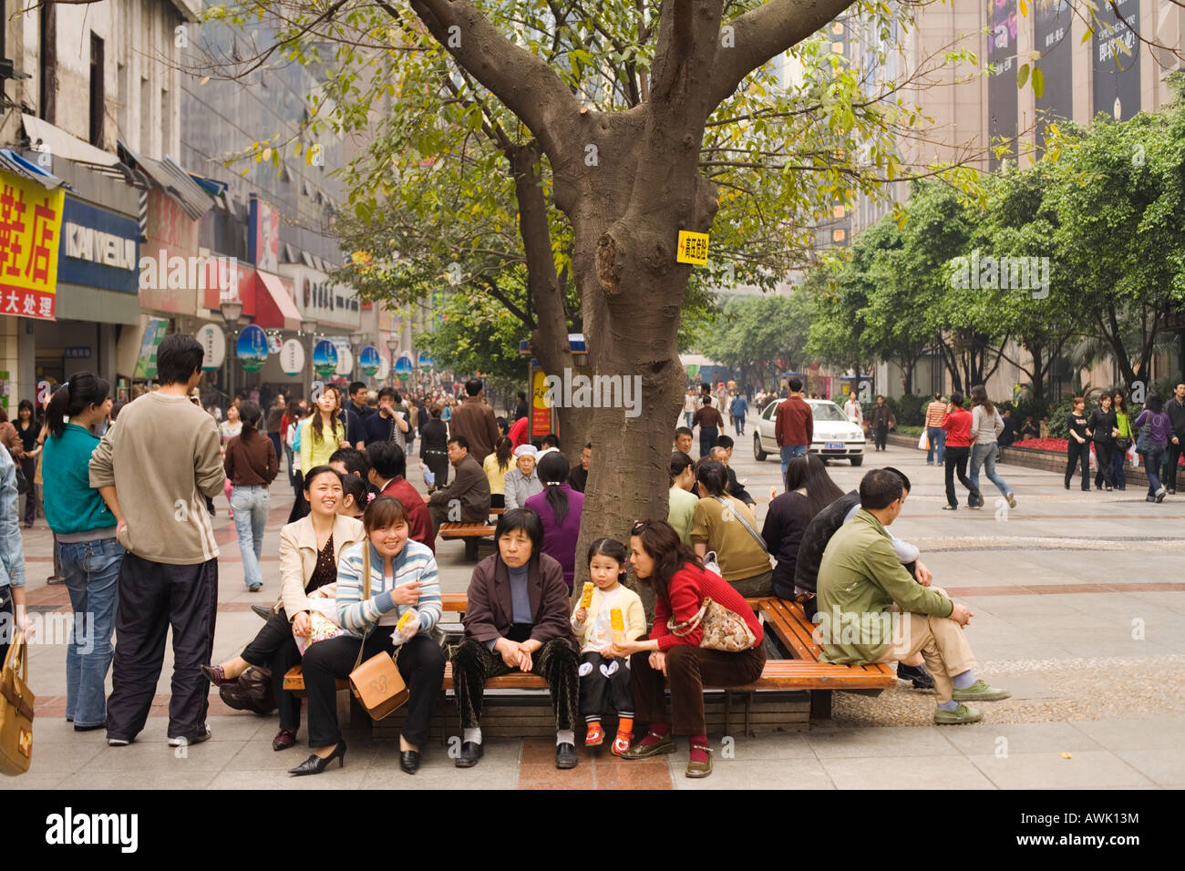 People sit under a tree in the city centre of Chongqing, The People's ...
