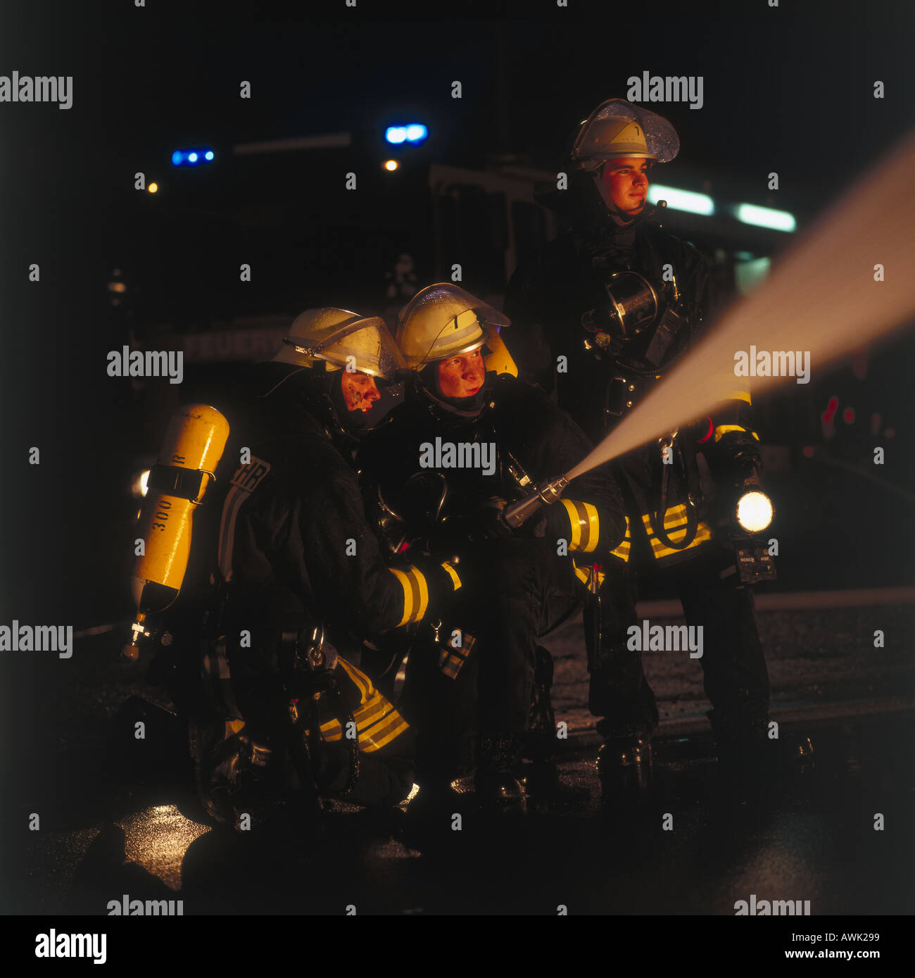 Two firemen spraying water on fire with hose Stock Photo - Alamy