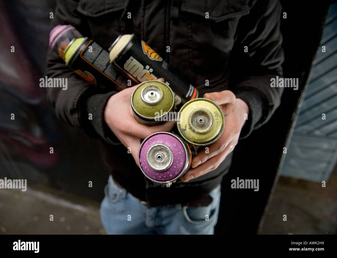 Graffiti Artist with mask spray paints a mural on a wall Stock Photo ...