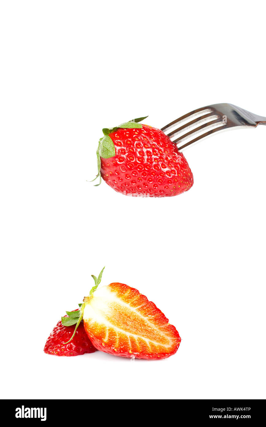 The fork pricking the strawberry and two half isolated on white ...