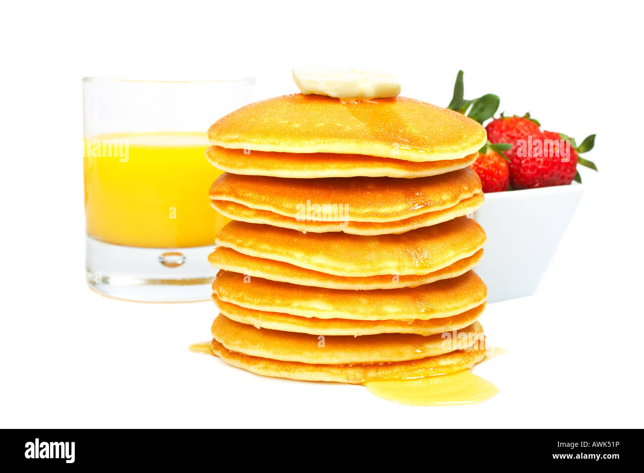 A big stack of pancakes with butter strawberries and orange juice on ...