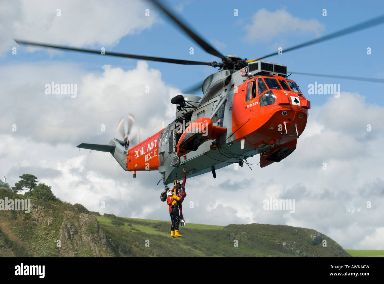 Royal Navy Sea King Helicopter hoisting two people from the sea as part ...