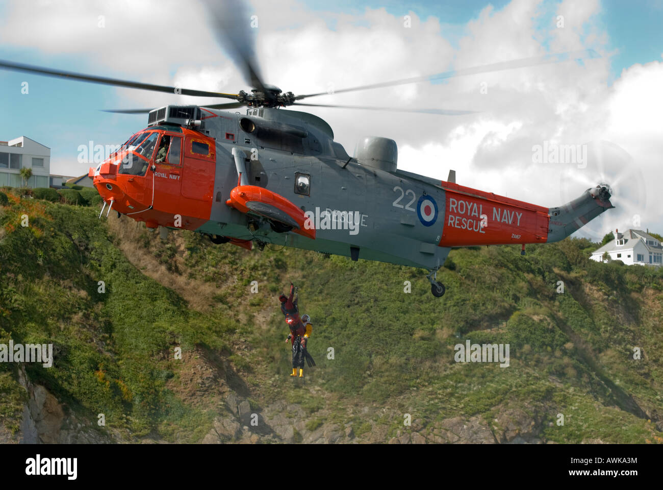 Royal Navy Sea King Helicopter hoisting two people from the sea as part ...