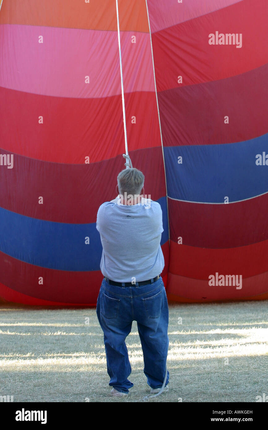 A worker holds on to a guide rope while a hot air balloon is inflated ...