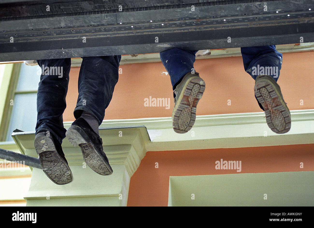 Legs of two construction workers sitting on a scaffolding, Riga, Latvia ...
