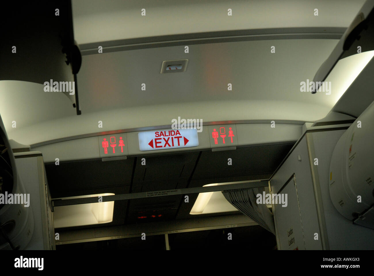 EXIT SALIDA SYMBOLS LIGHTED UP INSIDE AIRPLANE INTERIOR Stock Photo - Alamy