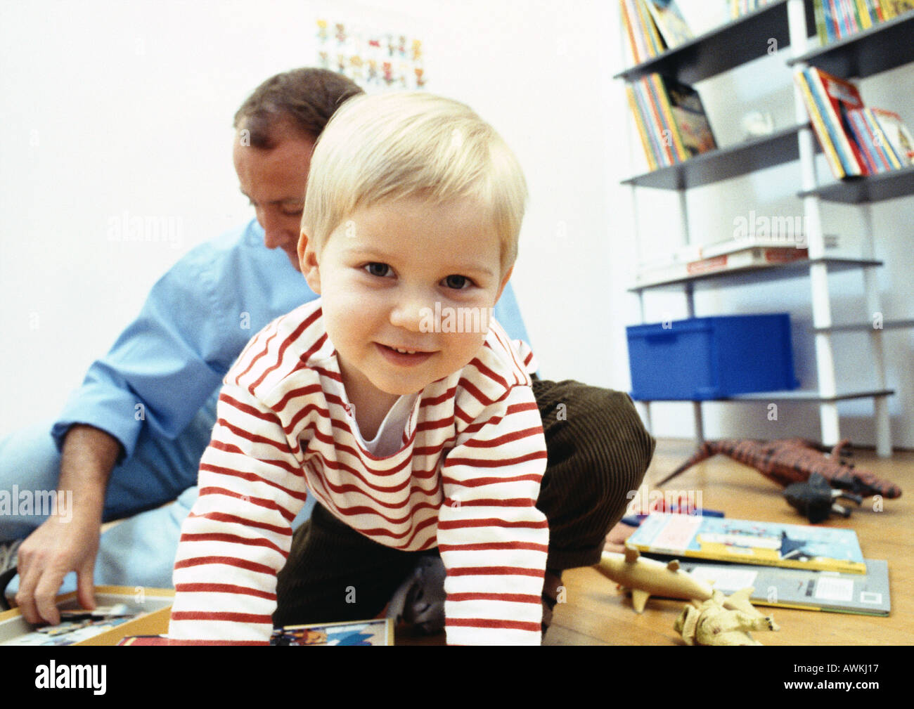 Young child facing camera in room with father Stock Photo - Alamy