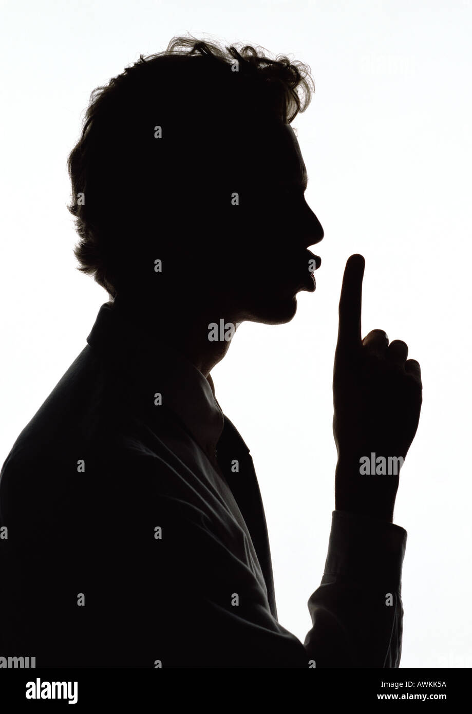 Man holding finger out in front of lips, silhouette Stock Photo - Alamy