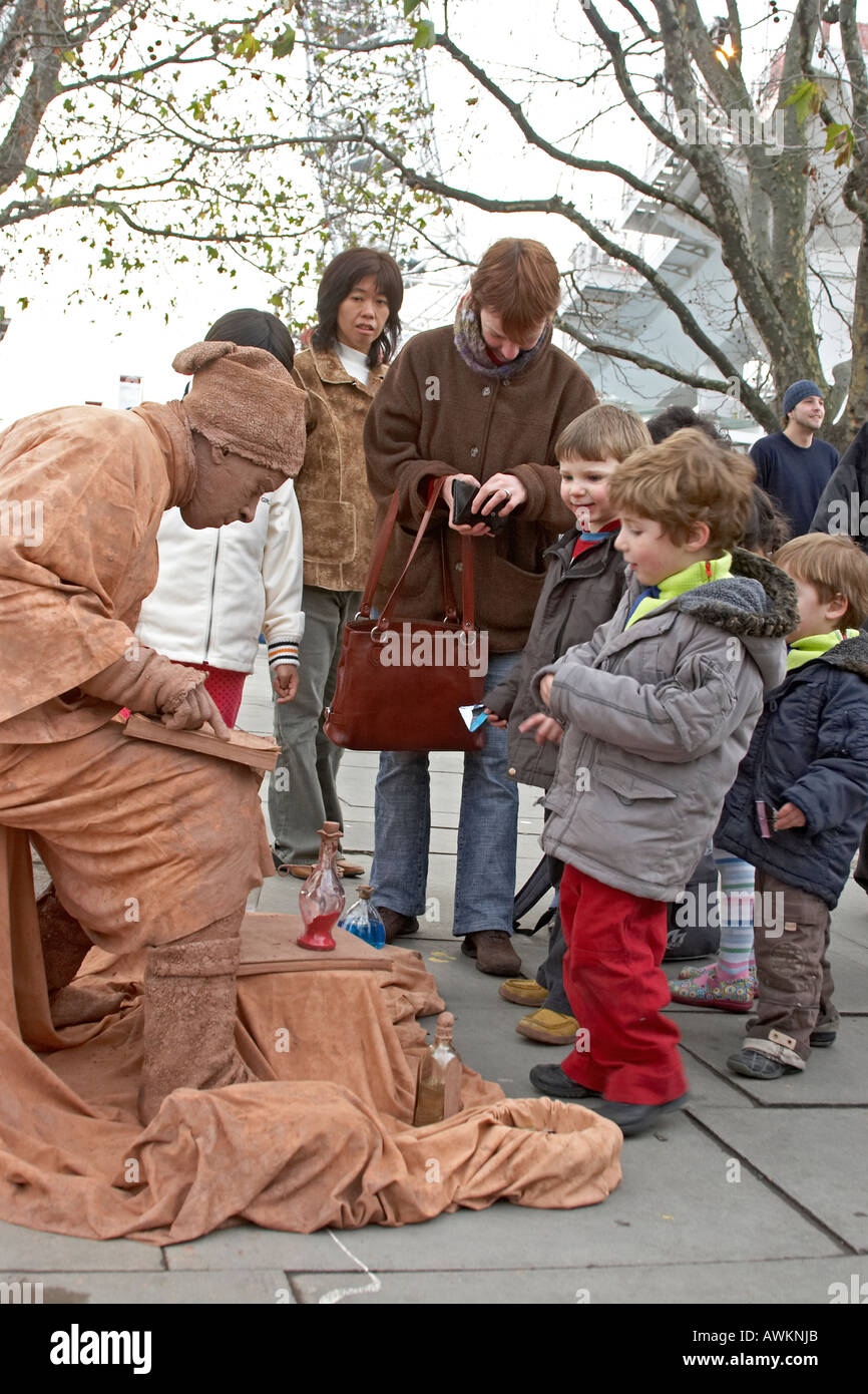 Children with human statue busker figure on South Bank on cloudy winter ...