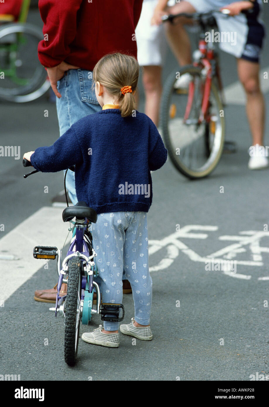 Little girl standing beside bicycle in bikelane, rear view Stock Photo ...