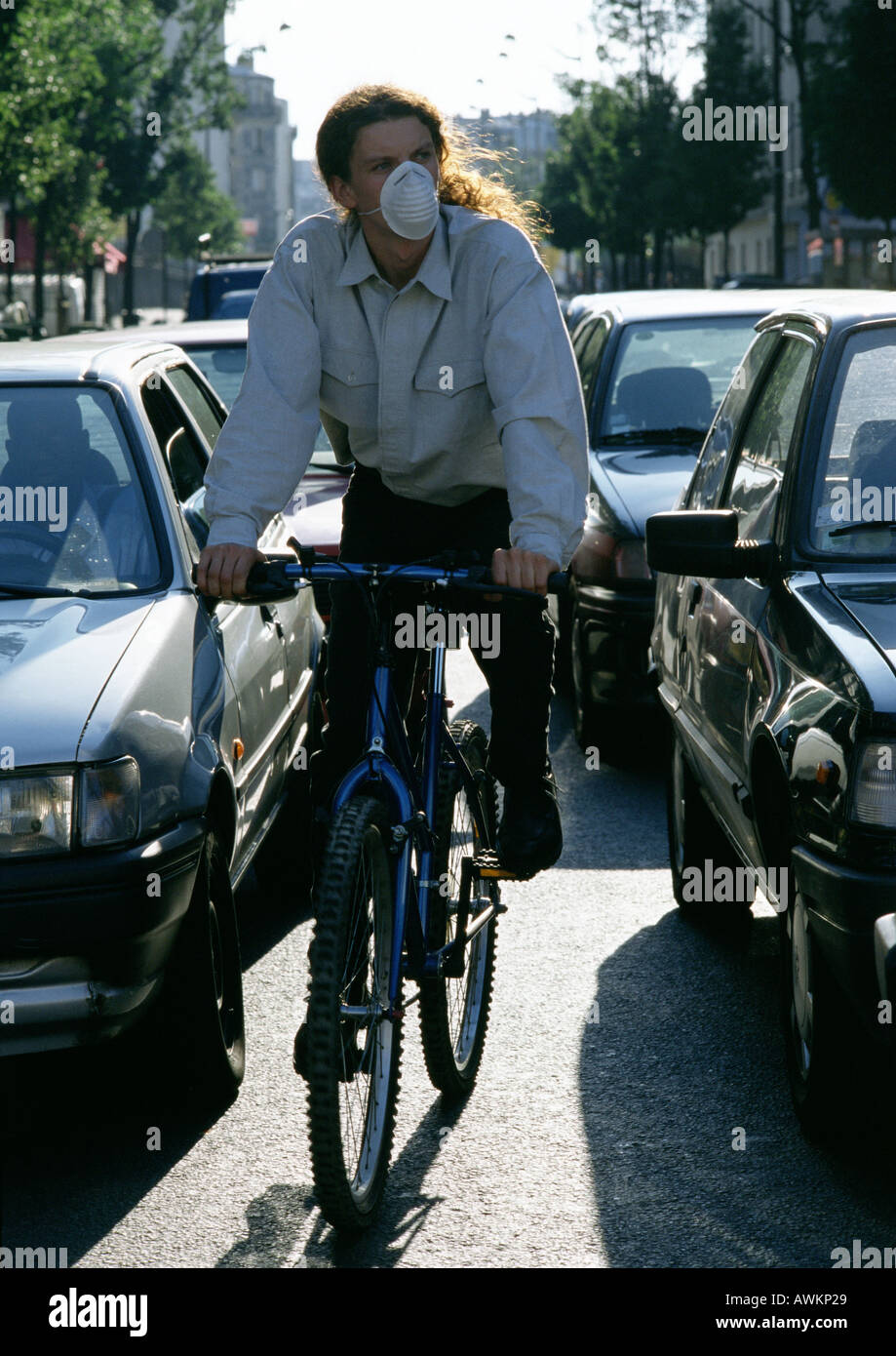 Cyclist riding in heavy traffic, wearing pollution mask Stock Photo - Alamy