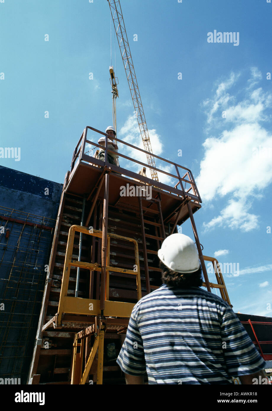 Worker looking up at man on scaffolding, low angle view Stock Photo - Alamy