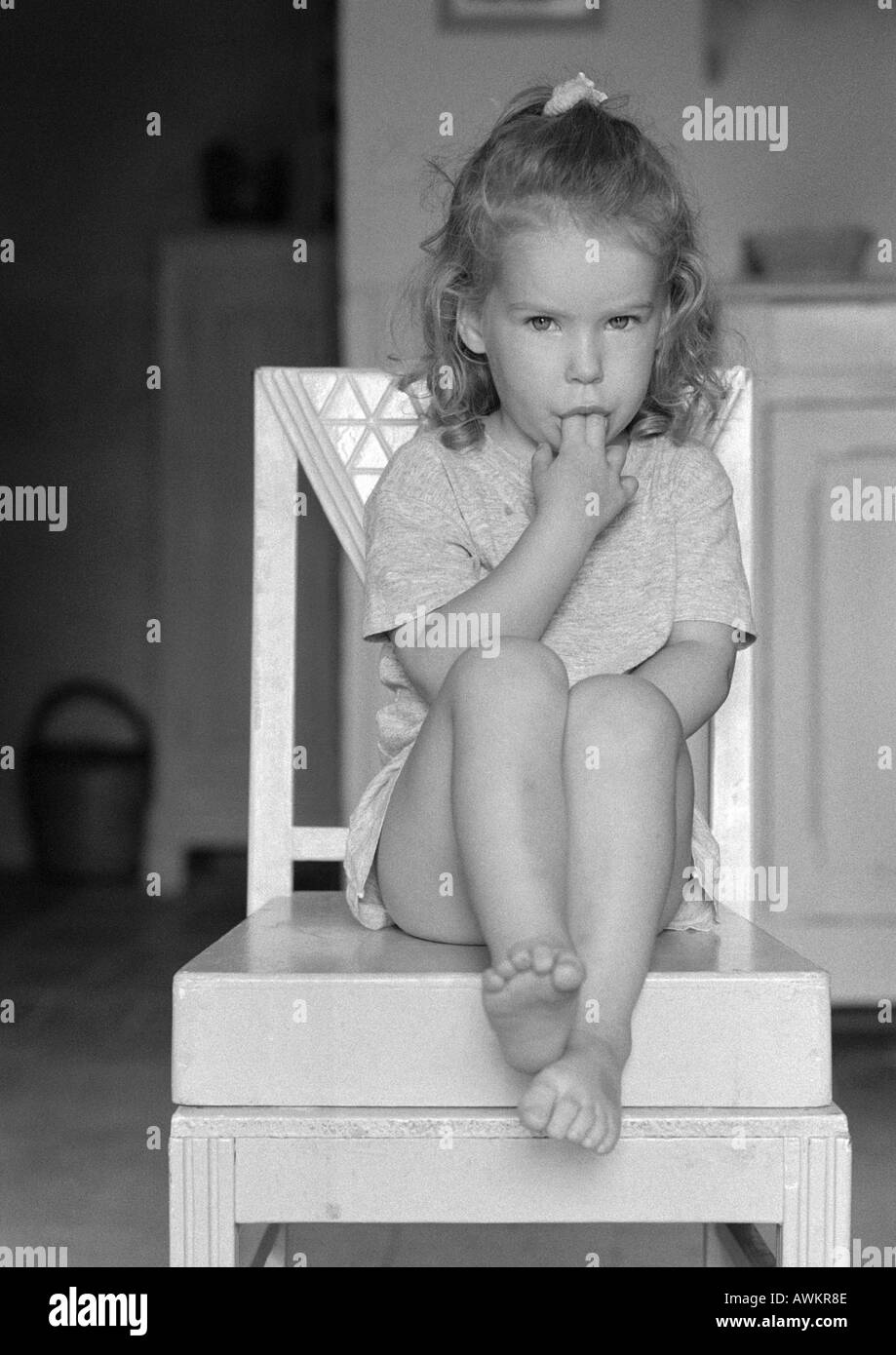 Little girl sitting with fingers in mouth, b&w Stock Photo - Alamy