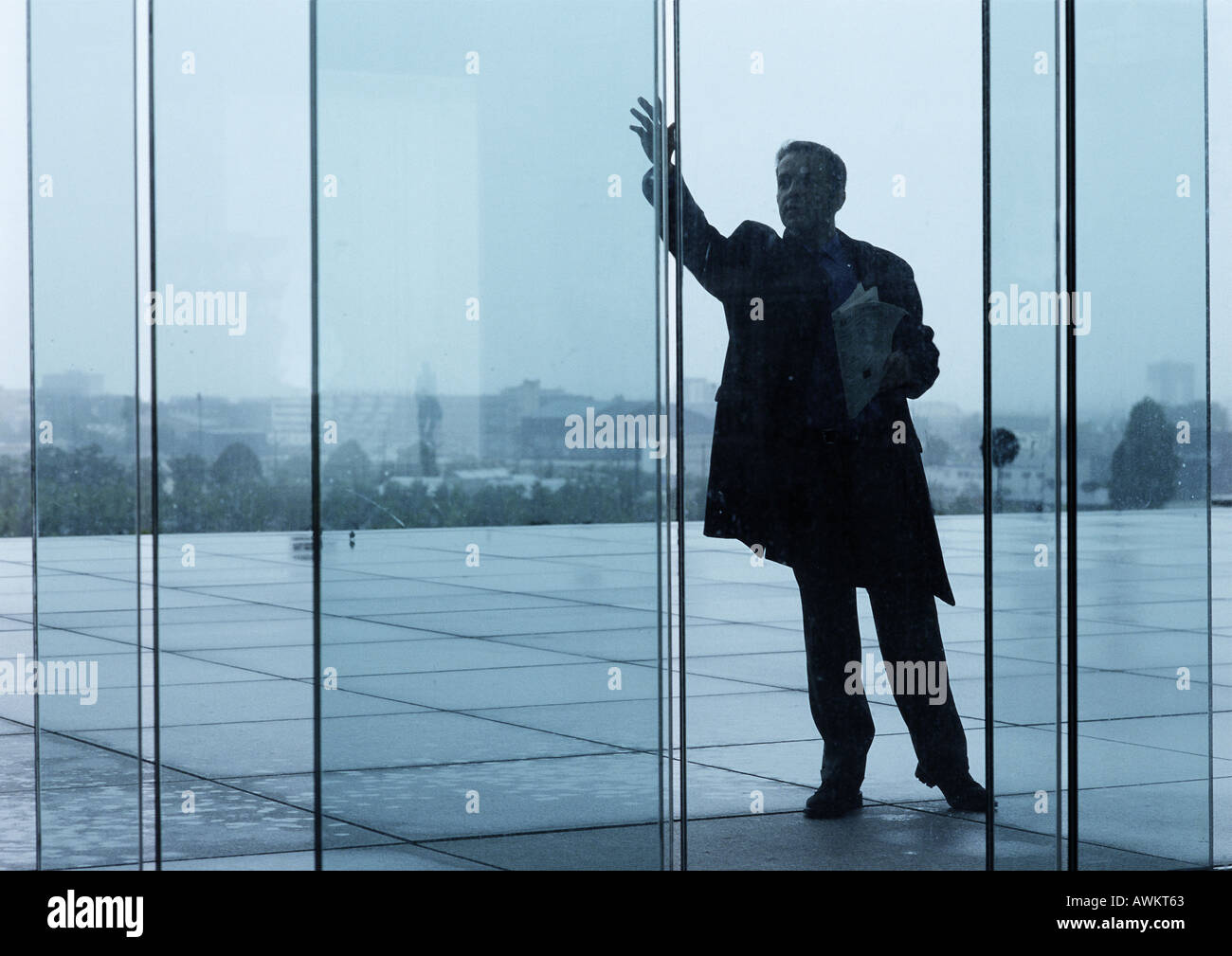 Man standing outside glass doors of building lobby, waving Stock Photo ...