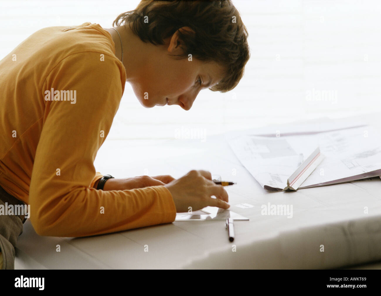 Woman bending over table, holding set square and pen, side view Stock ...