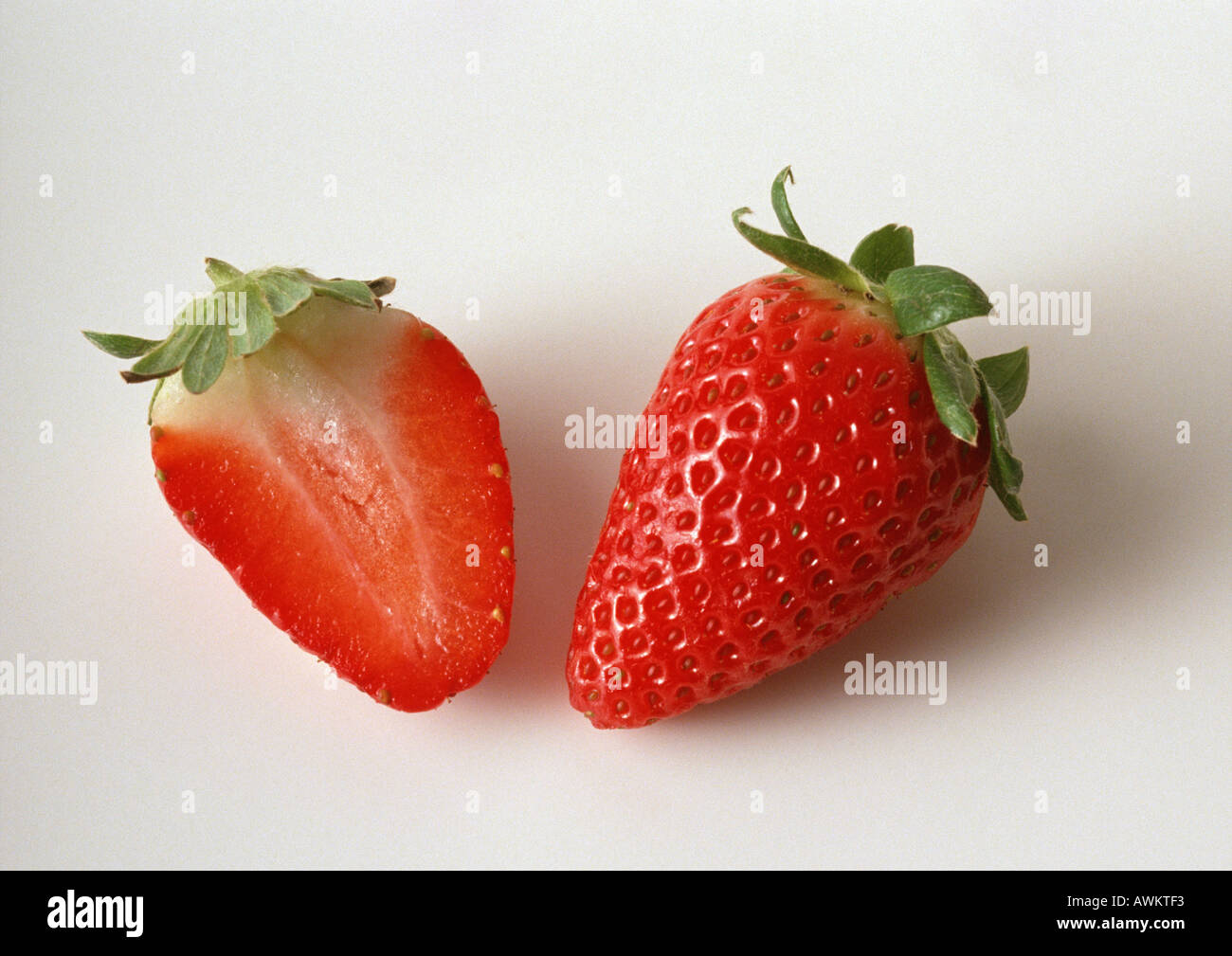Two strawberries, cross section of one, close-up, white background ...